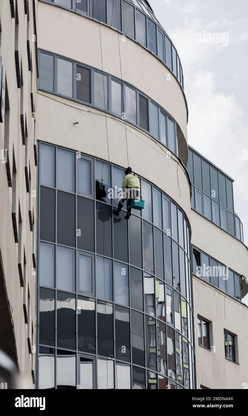 a worker at a height washes the windows of office building. dangerous ...