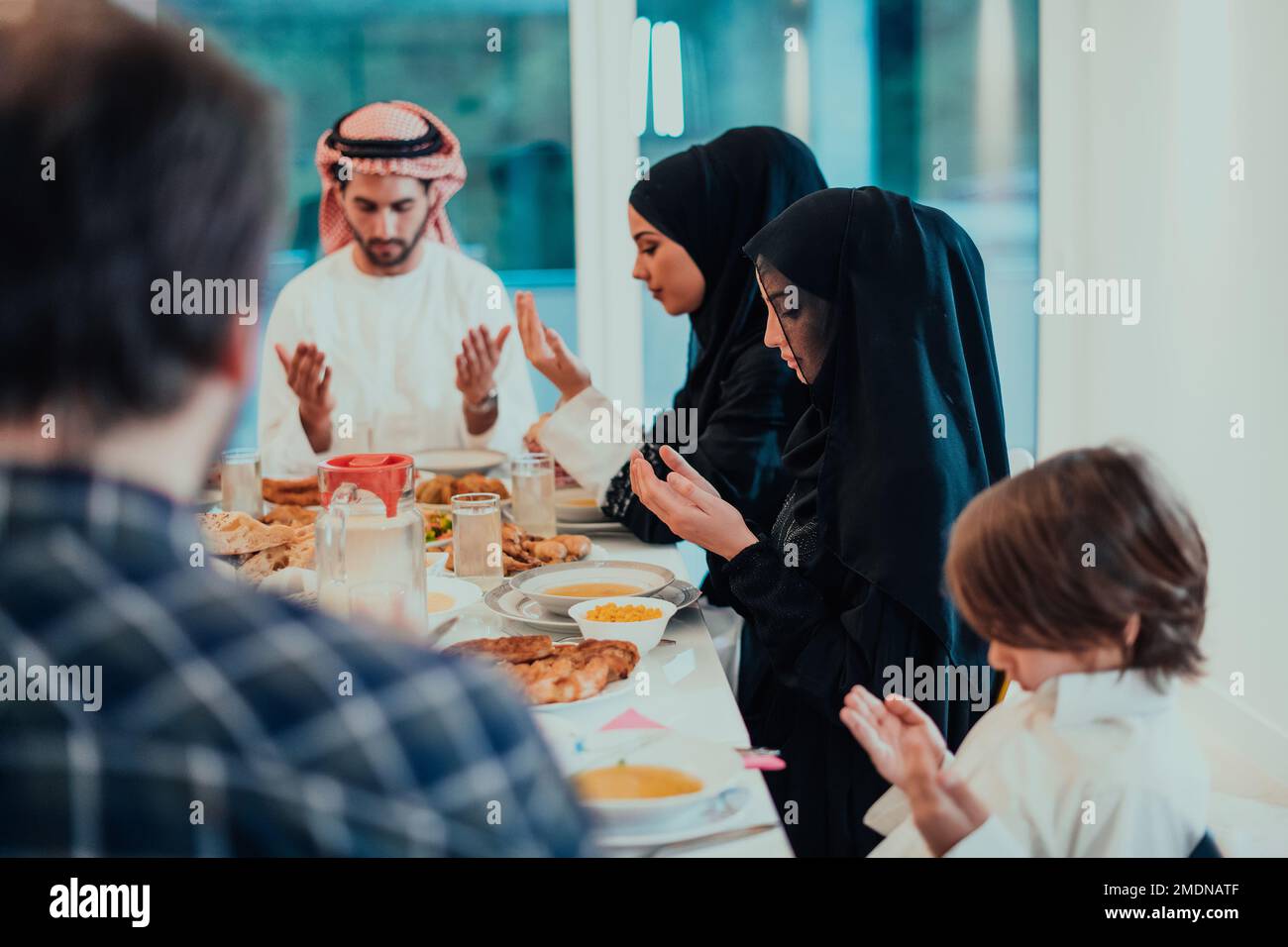 A Muslim family praying together, the Muslim prayer after breaking the ...