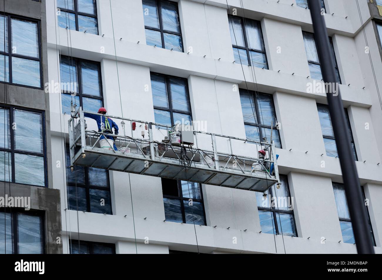 A worker in a cradle of a lifting mechanism. The process of insulating ...