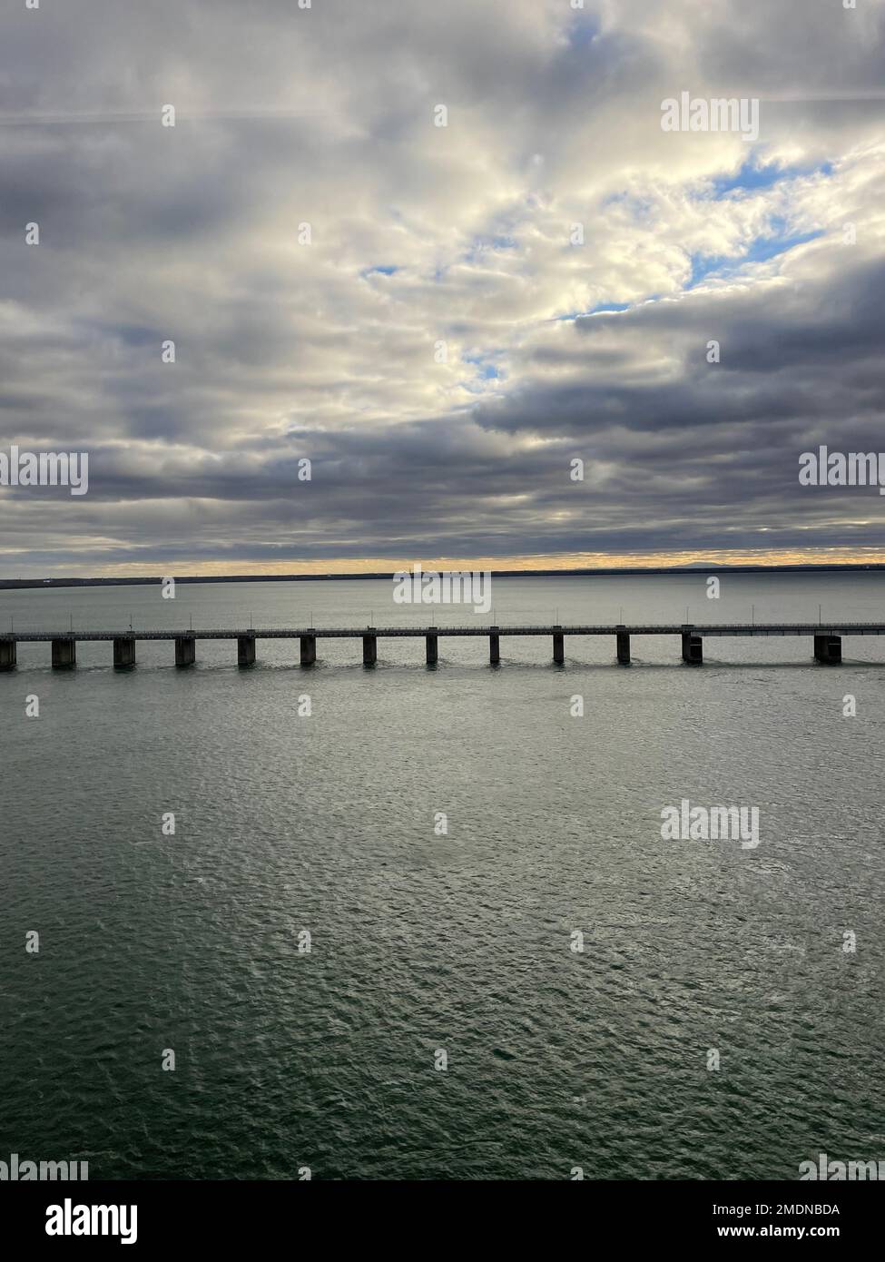 A long bridge in the ocean under the dark clouds Stock Photo - Alamy