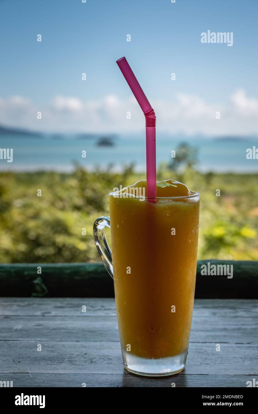 Fresh tropical mango drink with a straw on a restaurant table with a ...
