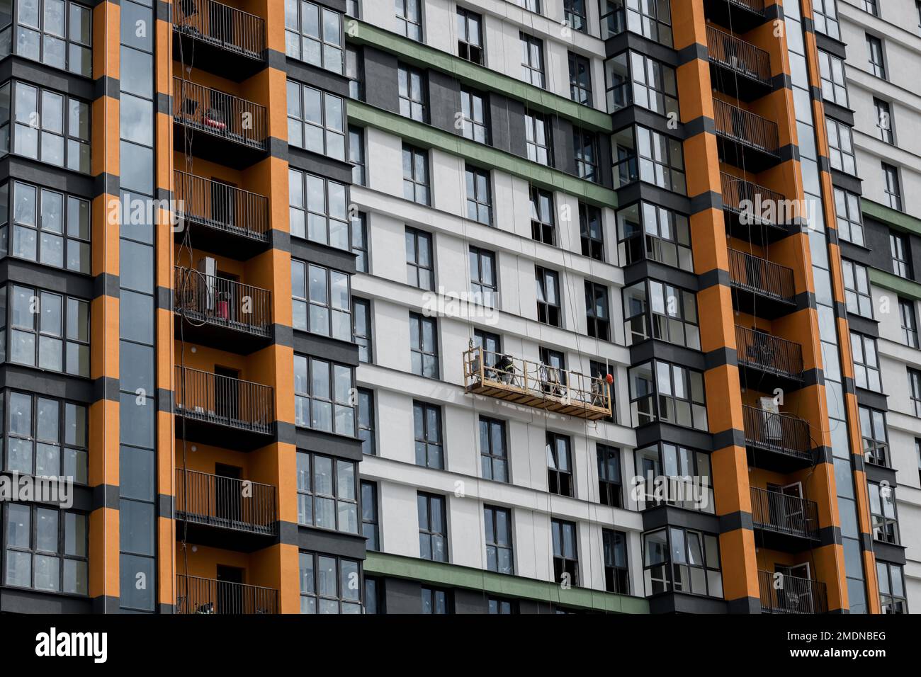 Facade with building cradle and worker. worker in the cradle on the ...