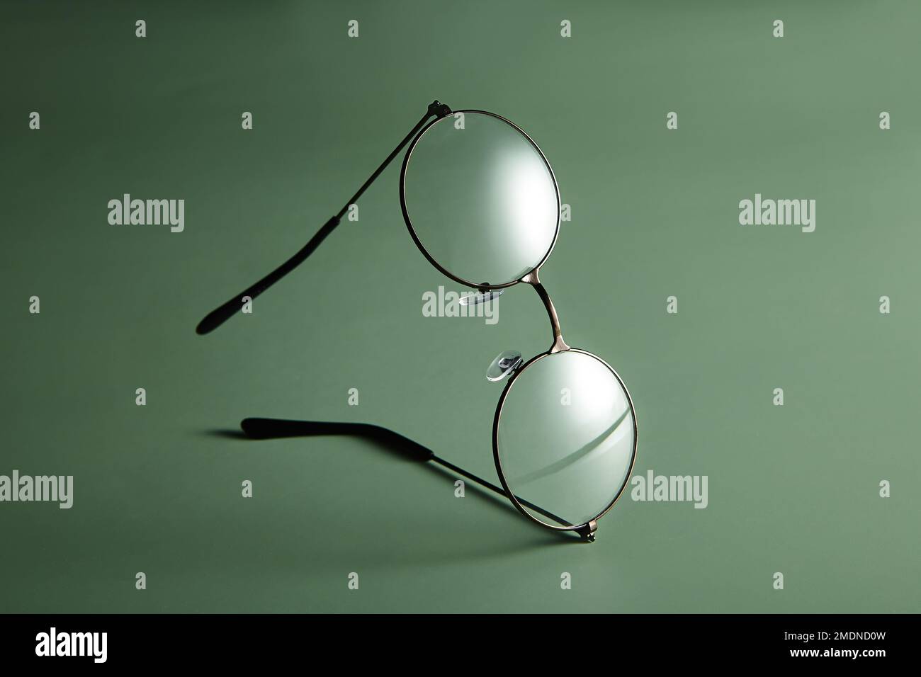 Open metal rimmed spectacles isolated on light-green Stock Photo - Alamy