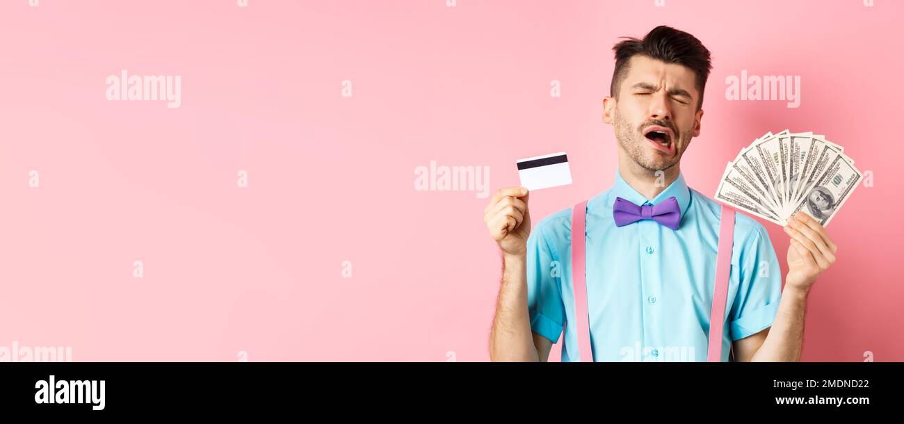 Sad crying man looking miserable, showing plastic credit card and money ...