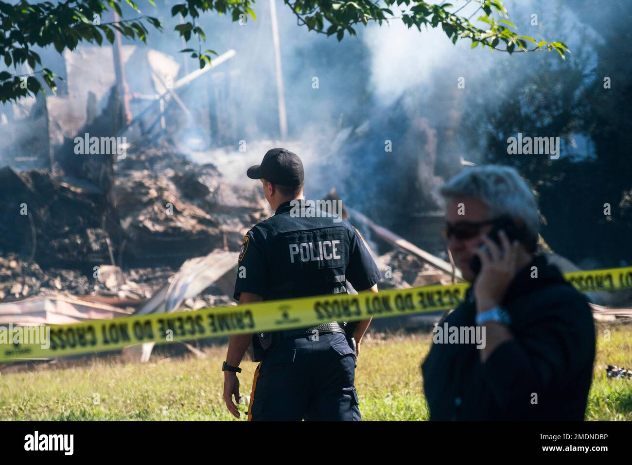 A Manville Police Officer stands guard near the remains of a house that ...