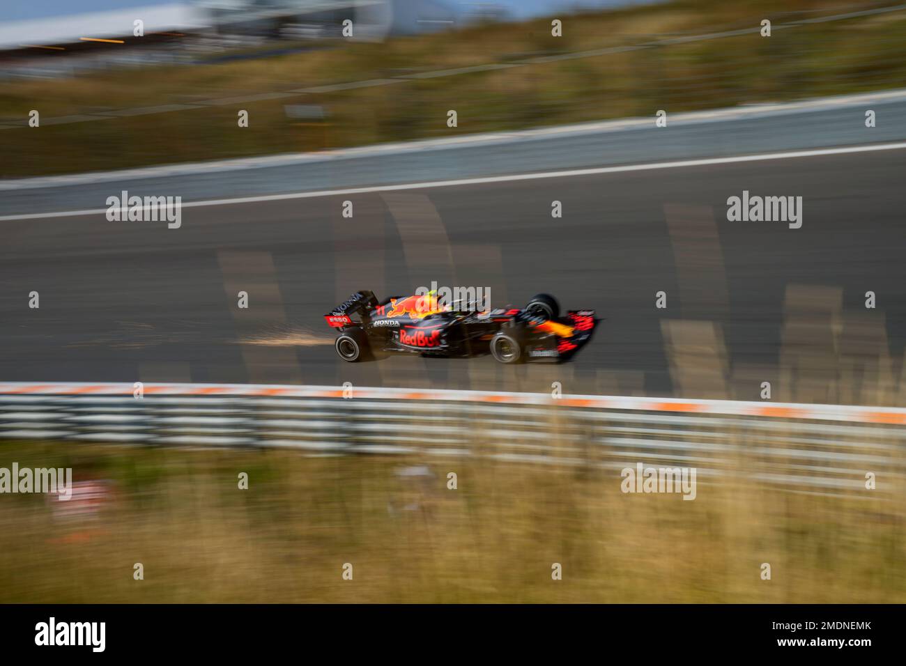 Sparks fly as Red Bull driver Sergio Perez of Mexico steers his car through one of the banked ...