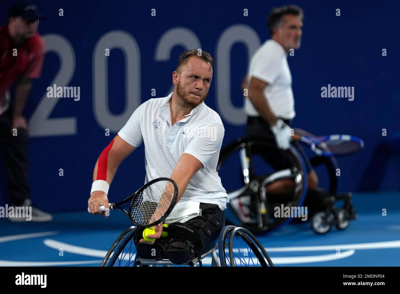France's Nicolas Peifer, front, serves as Stephane Houdet looks on ...