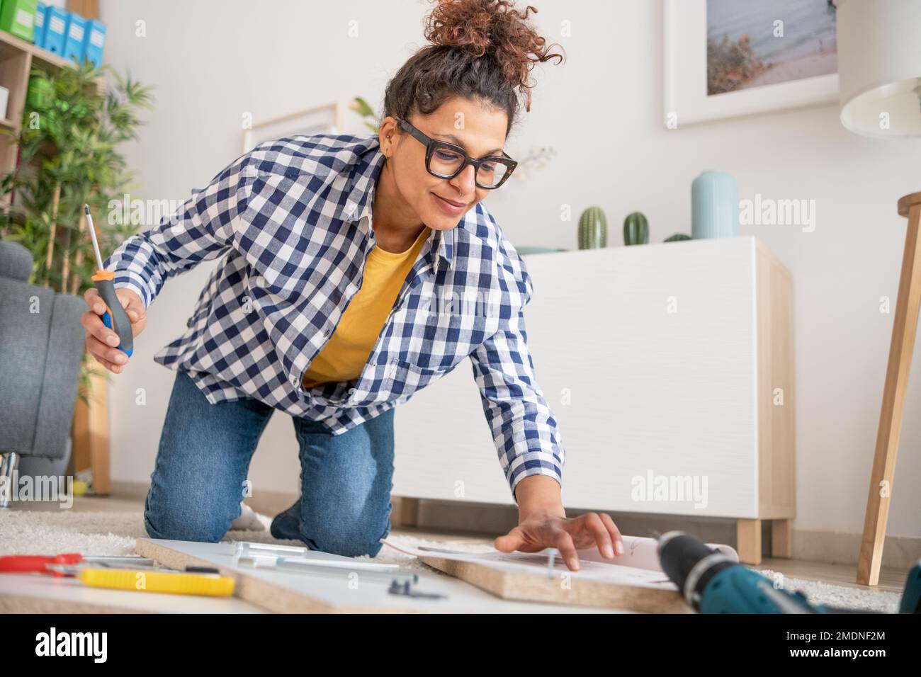 Black woman holding electric drill tool to assembly furniture in new ...