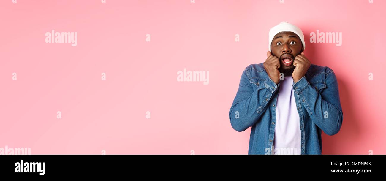 Scared and startled Black man gasping, staring at camera with hands ...