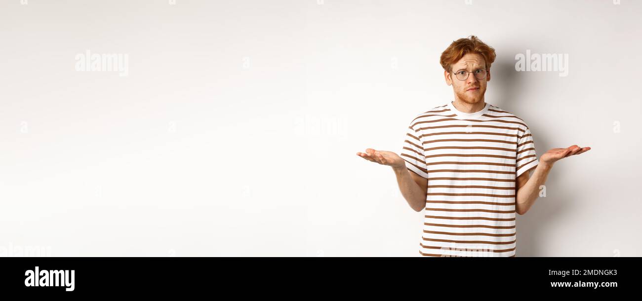 Confused boyfriend with red hair shrugging, spread hands sideways and ...