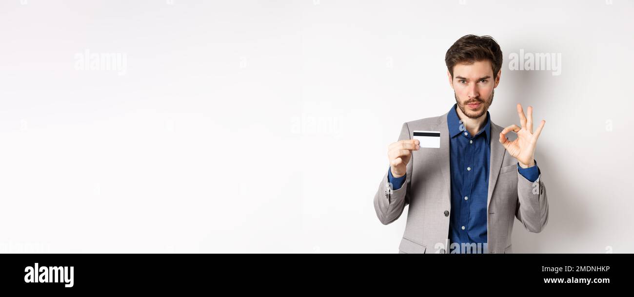 Happy male bank client in business suit showing plastic credit card and ...