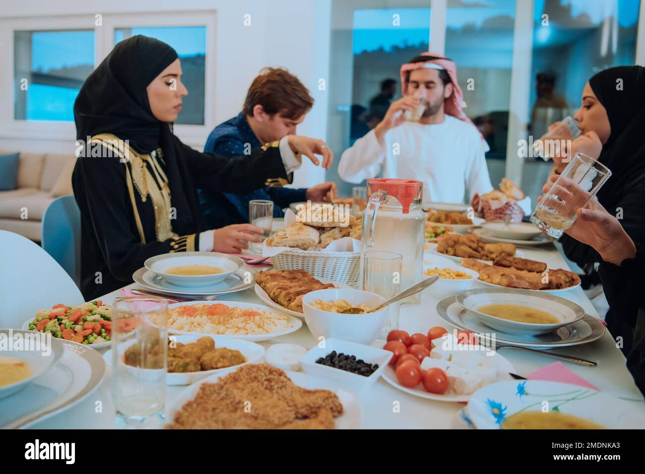 Muslim family having Iftar dinner drinking water to break feast. Eating ...