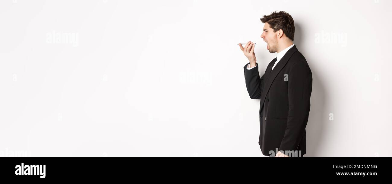 Profile shot of angry businessman in black suit, shouting at ...