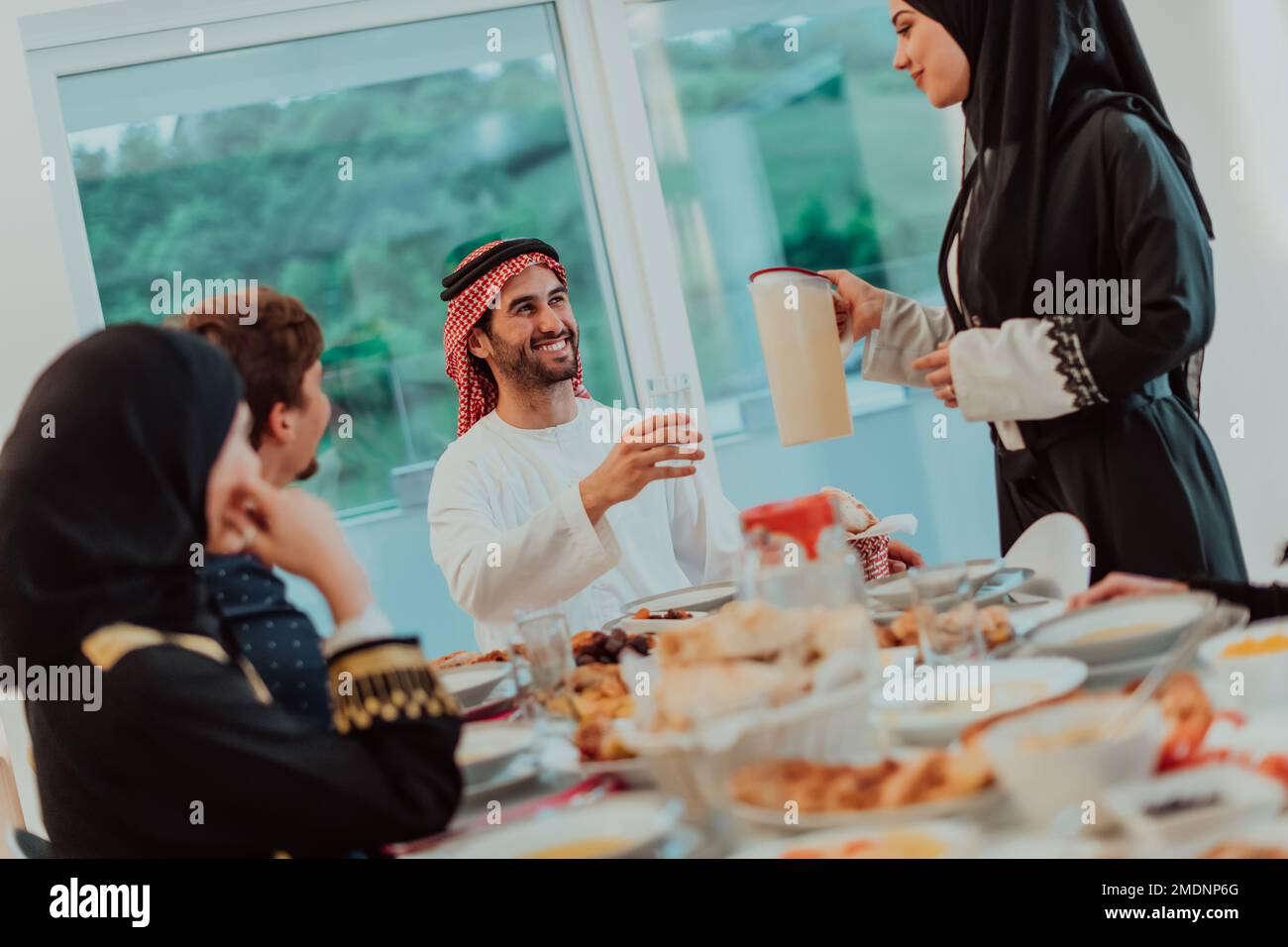 Muslim family having Iftar dinner drinking water to break feast. Eating ...