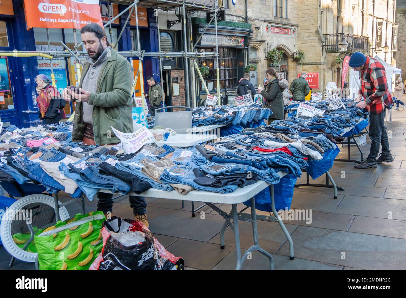 People buying second hand denim jeans on an outdoor market stall in ...