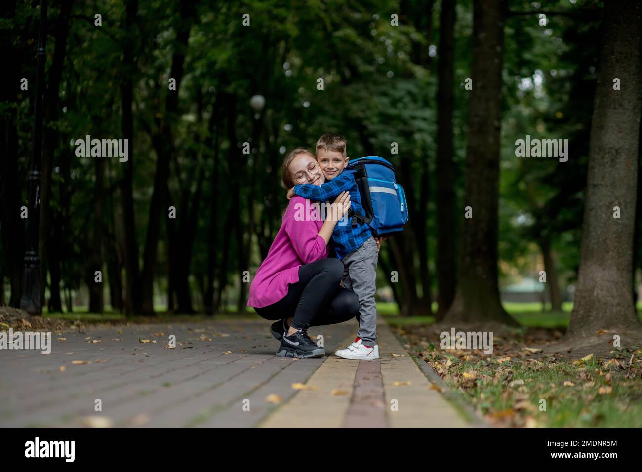 Young mother embraces her excited first class son on the way to school ...
