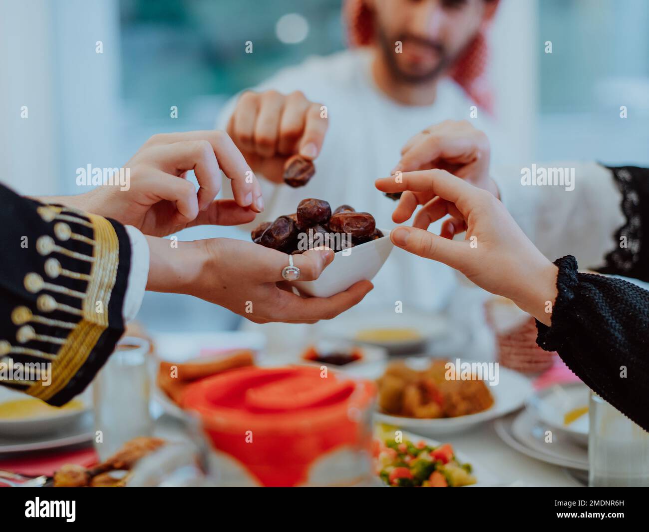 Muslim family having Iftar dinner drinking water to break feast. Eating traditional food during ...