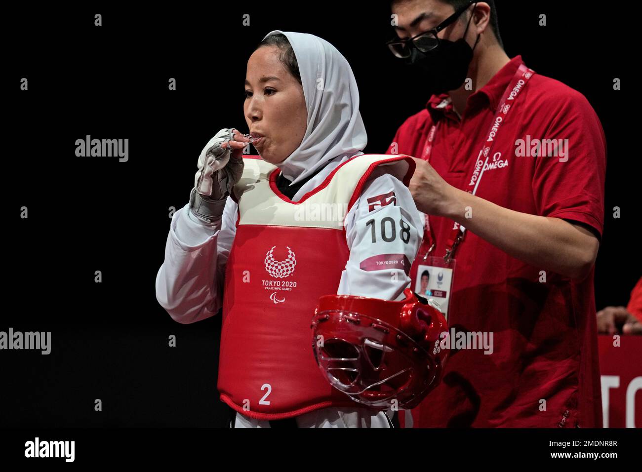 A game official assists Afghanistan's Zakia Khudadadi to wear ...