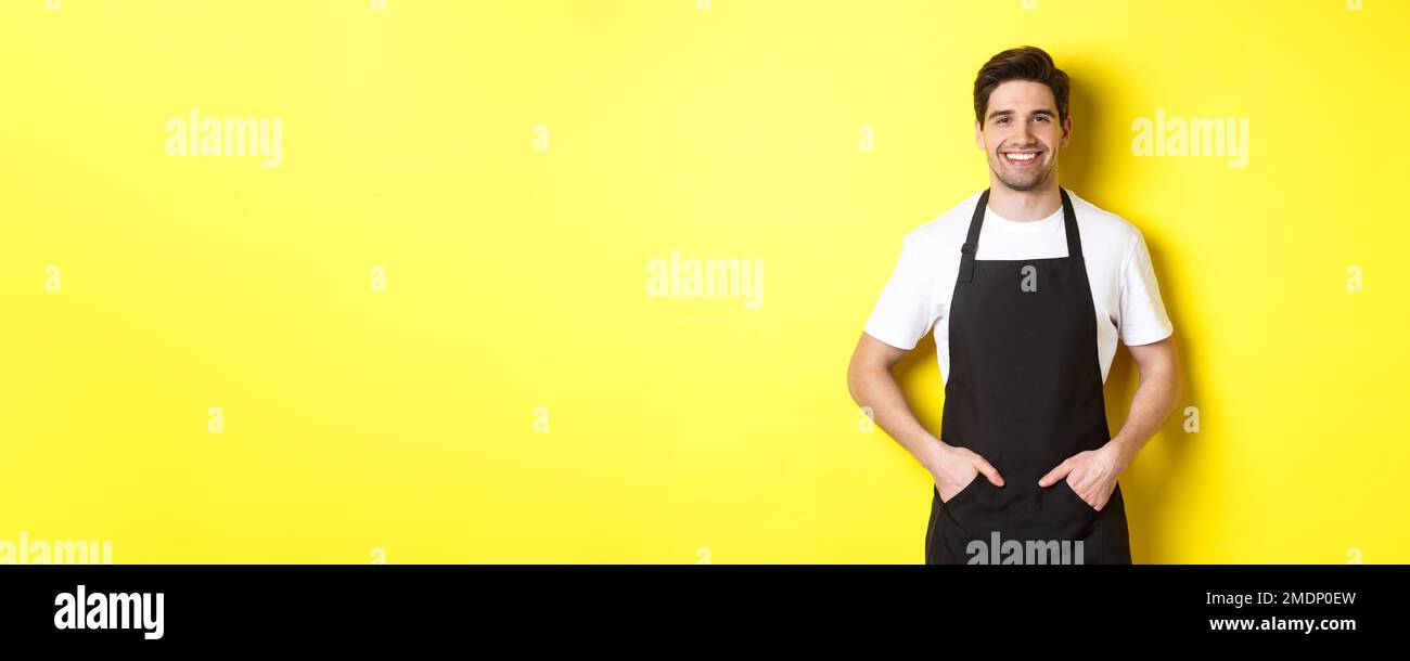 Happy barista in black apron looking at camera. Coffee shop owner ...