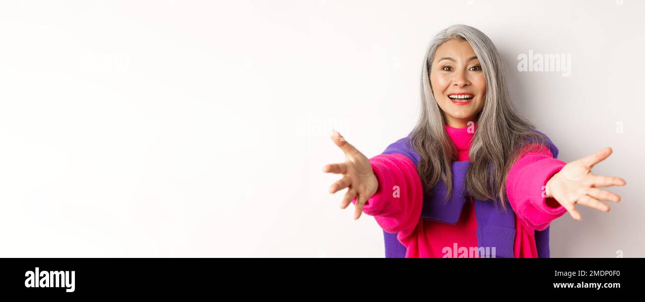 Close-up of stylish asian mature woman reaching hands forward ...