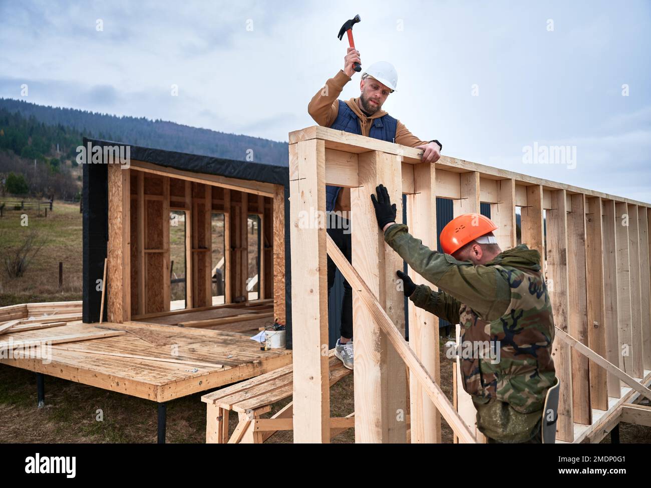 Man worker building wooden frame house on pile foundation. Carpenter ...