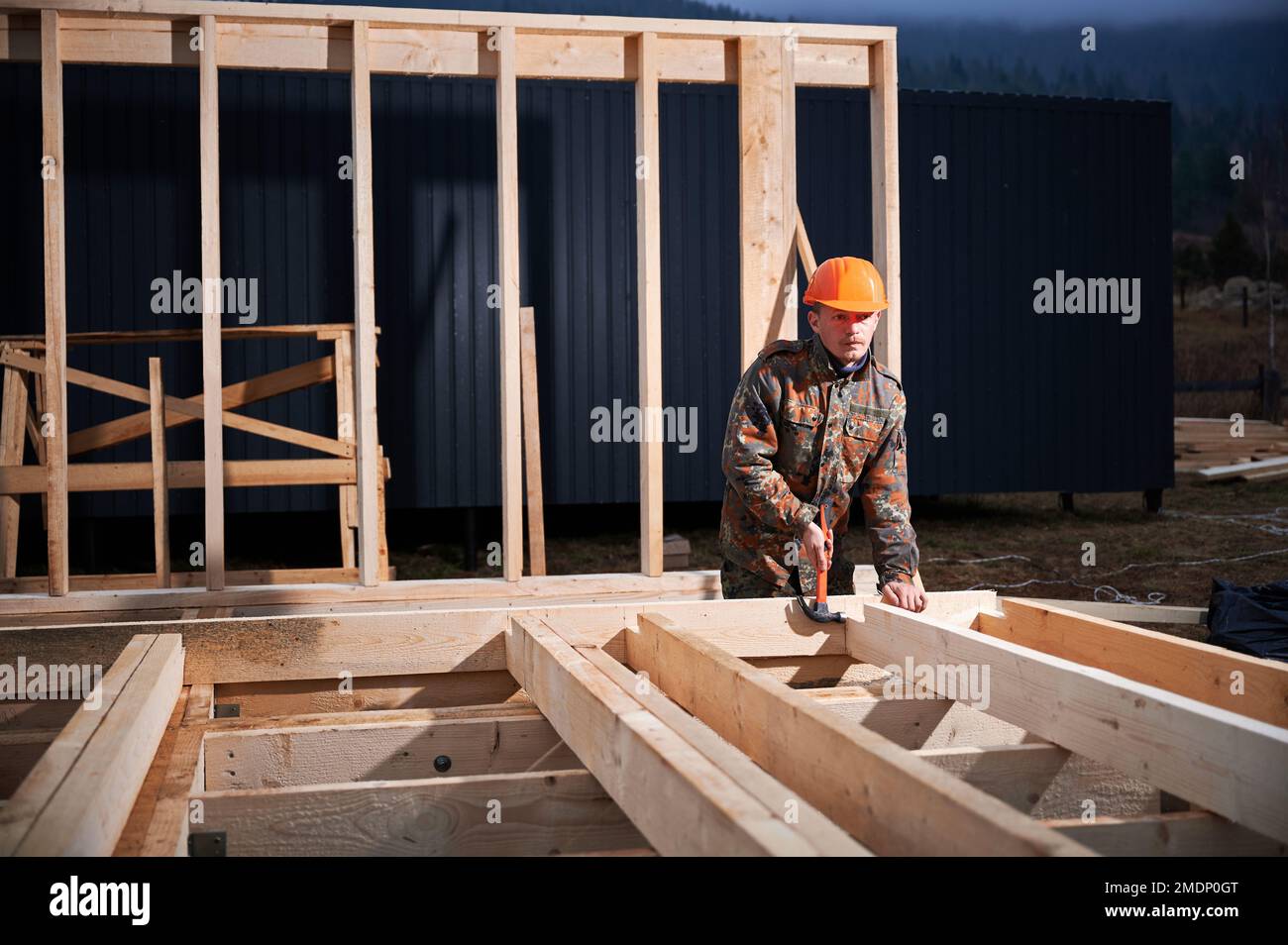 Man worker building wooden frame house on pile foundation. Carpenter ...
