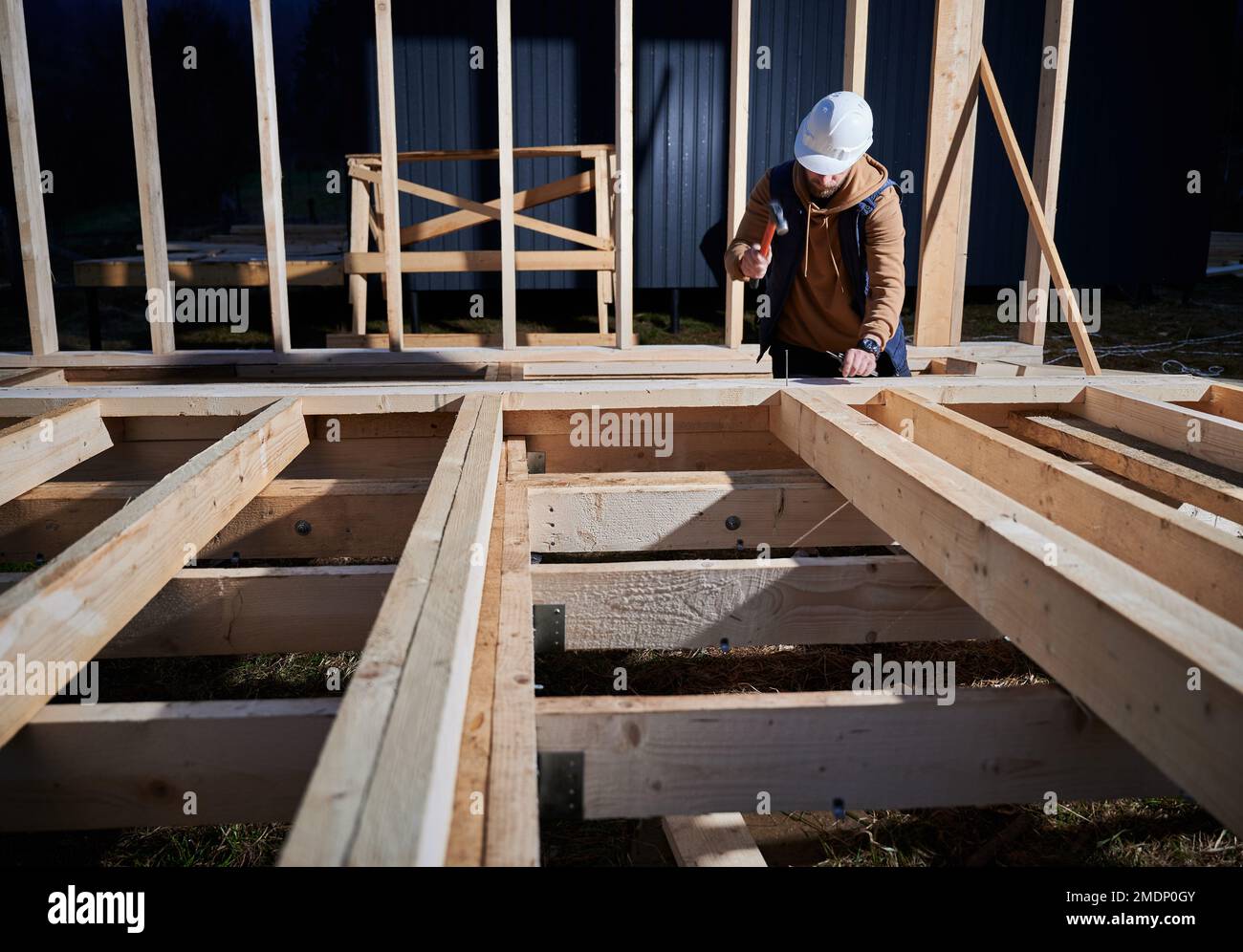 Man worker building wooden frame house on pile foundation. Carpenter ...