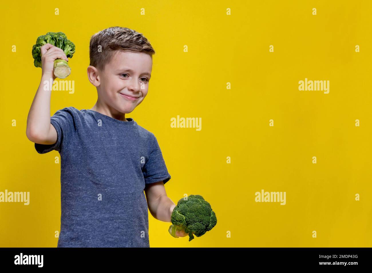 Healthy food, green vegetables broccoli in the hands of a cheerful boy ...