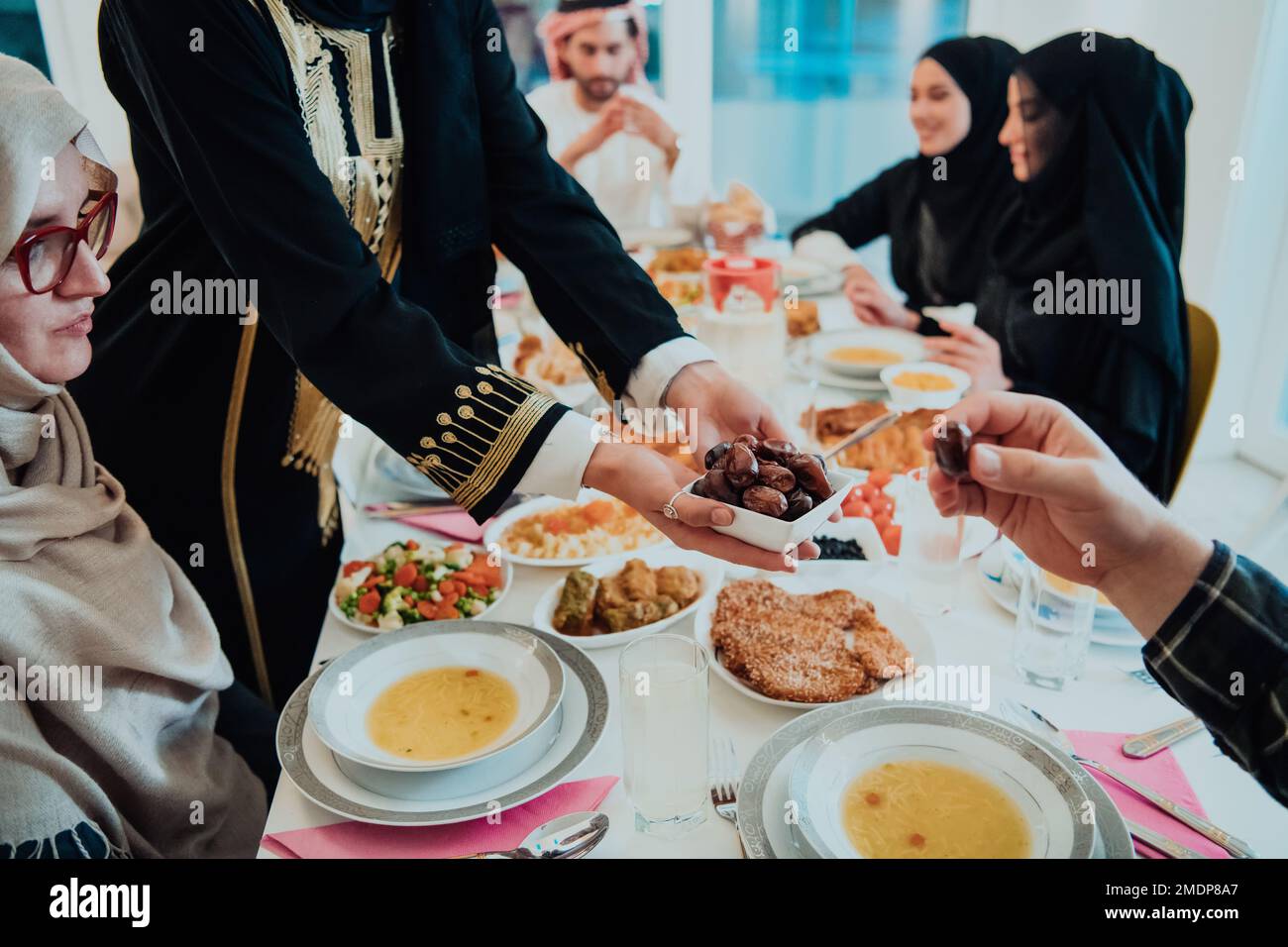 Muslim family having Iftar dinner drinking water to break feast. Eating traditional food during ...