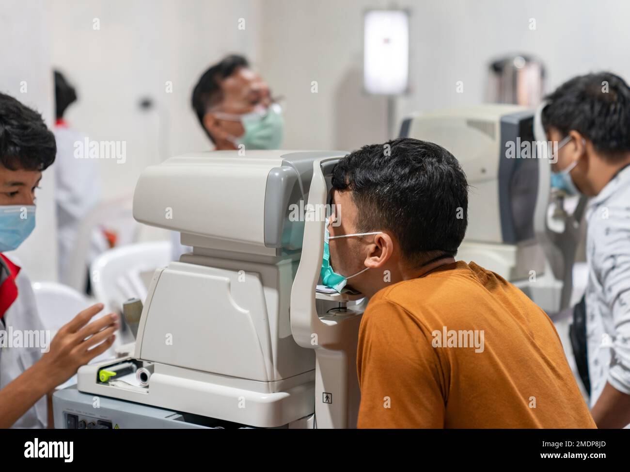 Optometrist with patient, giving an eye examination in annual health ...