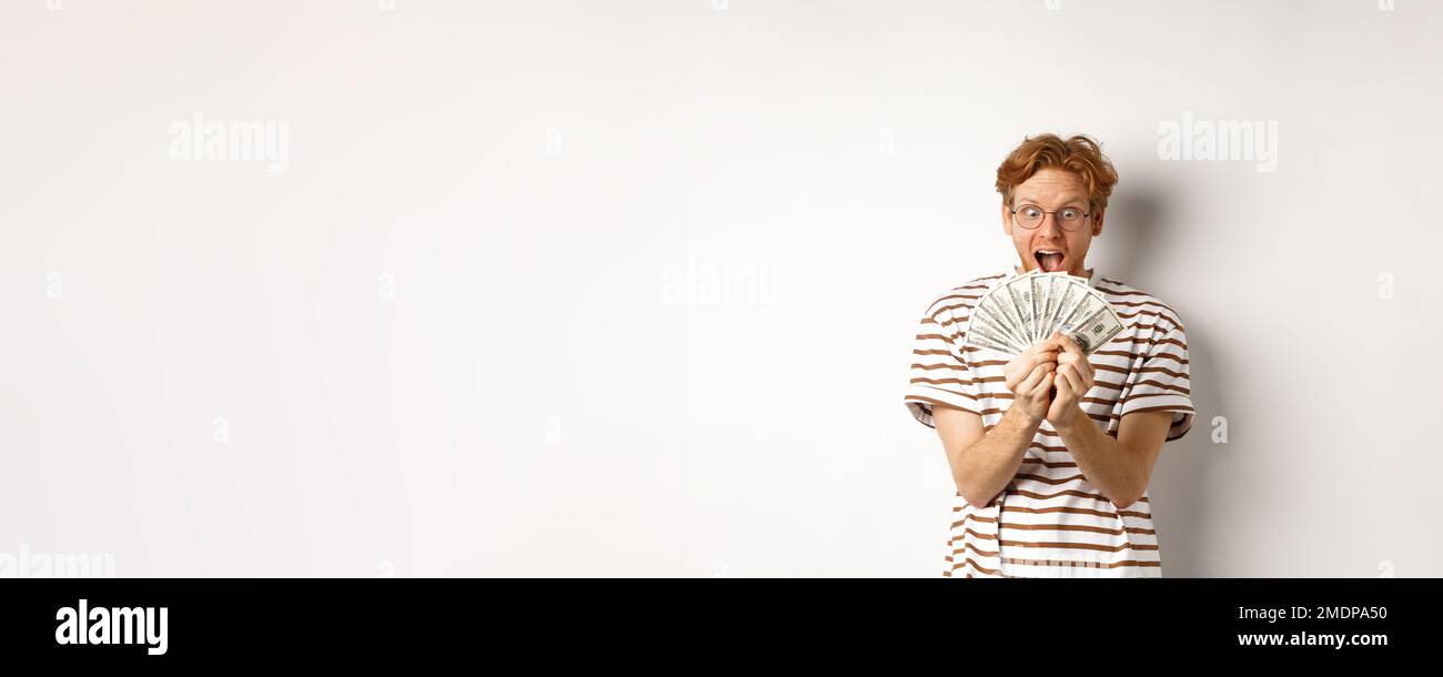 Lucky young man with red hair showing dollars, winning money and ...