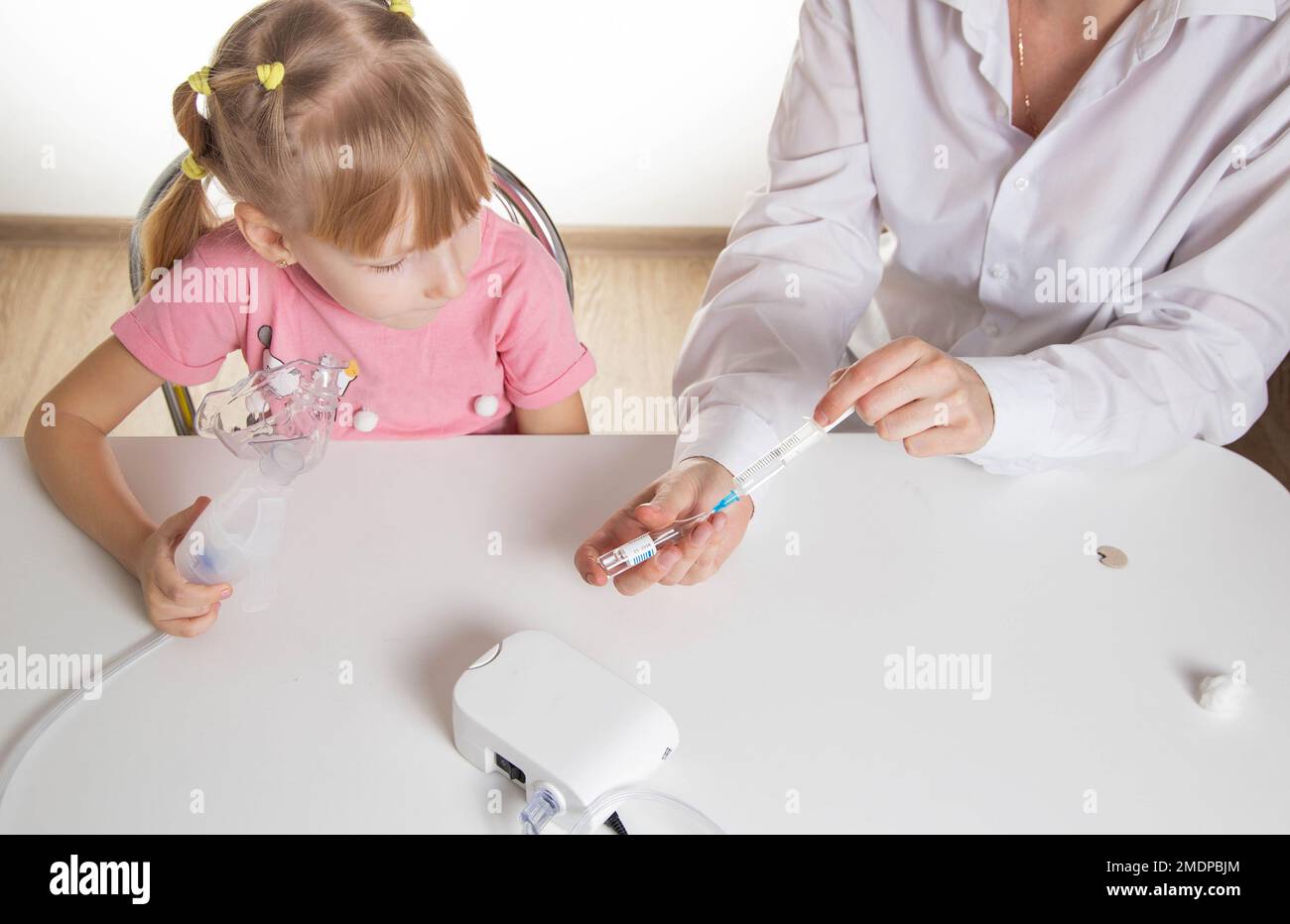 A doctor is putting a drug into a nebulizer for the treatment of ...