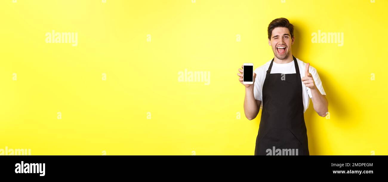 Happy waiter showing mobile screen and thumb up, recommending cafe ...