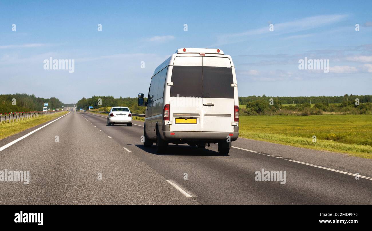 Passenger minibus moves along the motorway in summer against the blue ...
