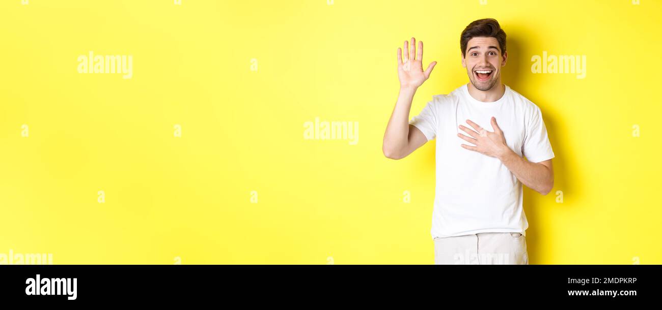 Happy guy making promise, holding hand on heart, swearing to tell truth ...