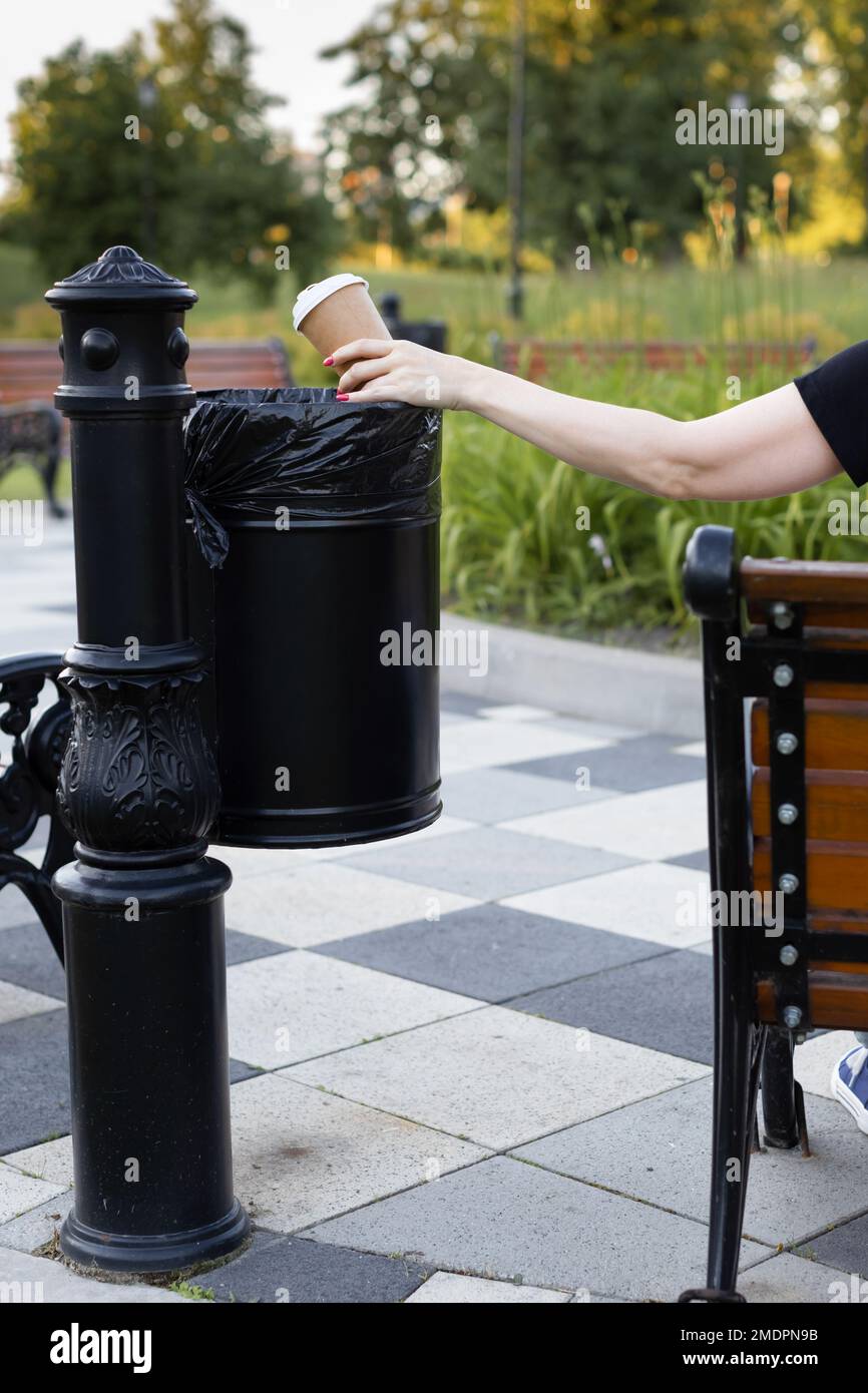 man throws a paper cup into the trash. man throws out a disposable ...