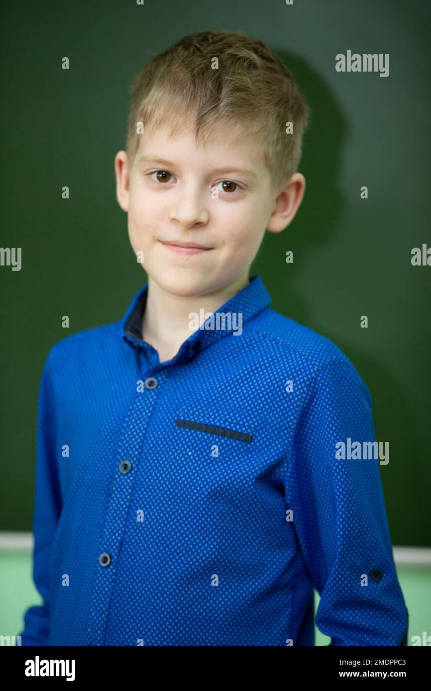 Vertical portrait of a schoolboy at the blackboard. The boy is ten ...