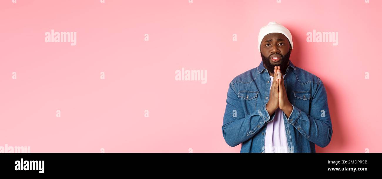 Upset african-american man asking for help, holding hands in pray ...