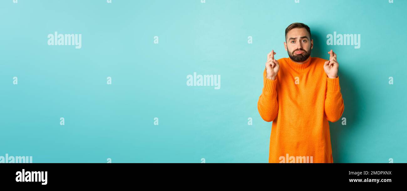 Hopeful sad man making a wish, cross fingers for good luck and sulking ...