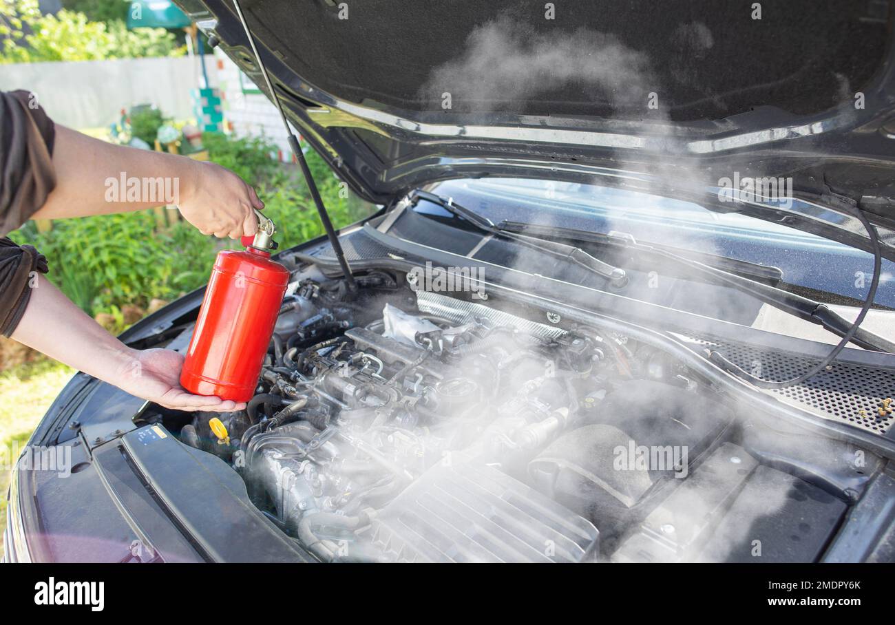 The driver of the car directs a powder fire extinguisher at the engine ...