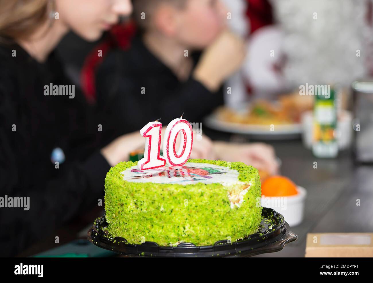 Festive cake with the number ten on the background of blurry guests ...