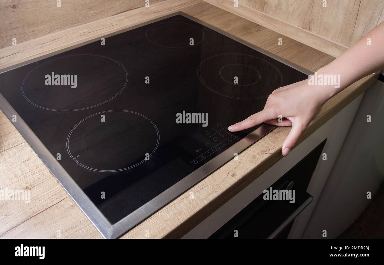 A woman's finger presses the inclusion of a modern induction hob in the ...