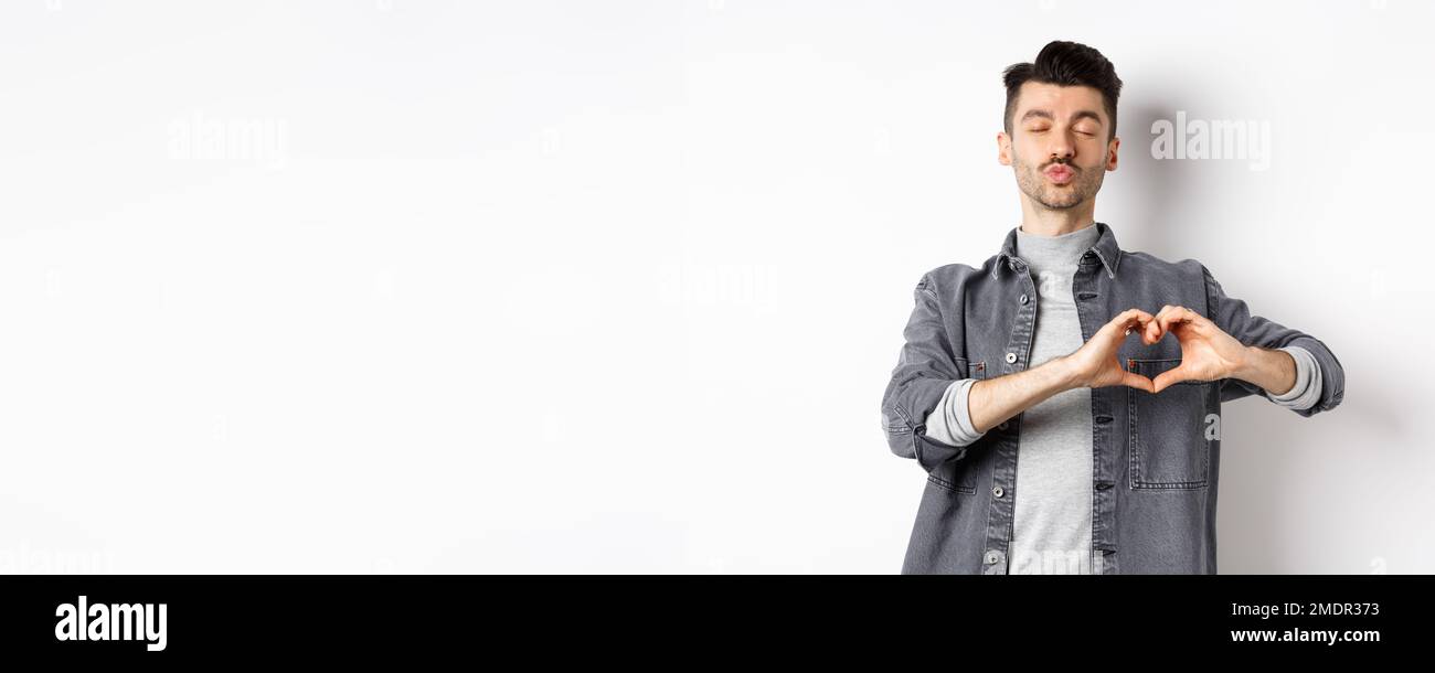 Cute young man waiting for kiss and showing heart gesture, confess on ...