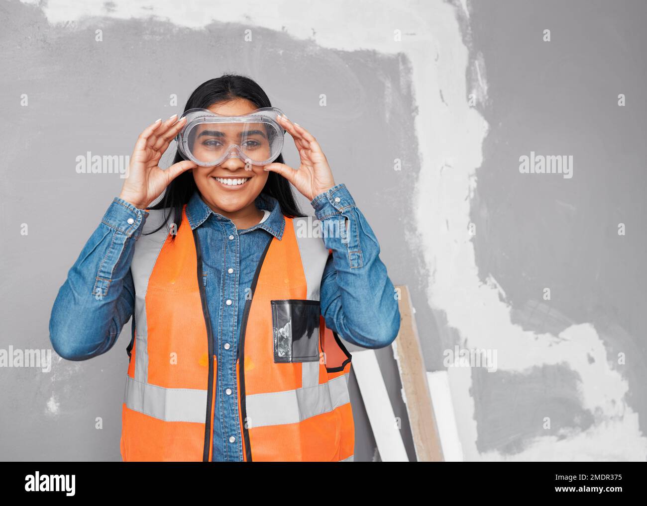 A female construction worker smiles and fits her safety goggles while on site Stock Photo - Alamy