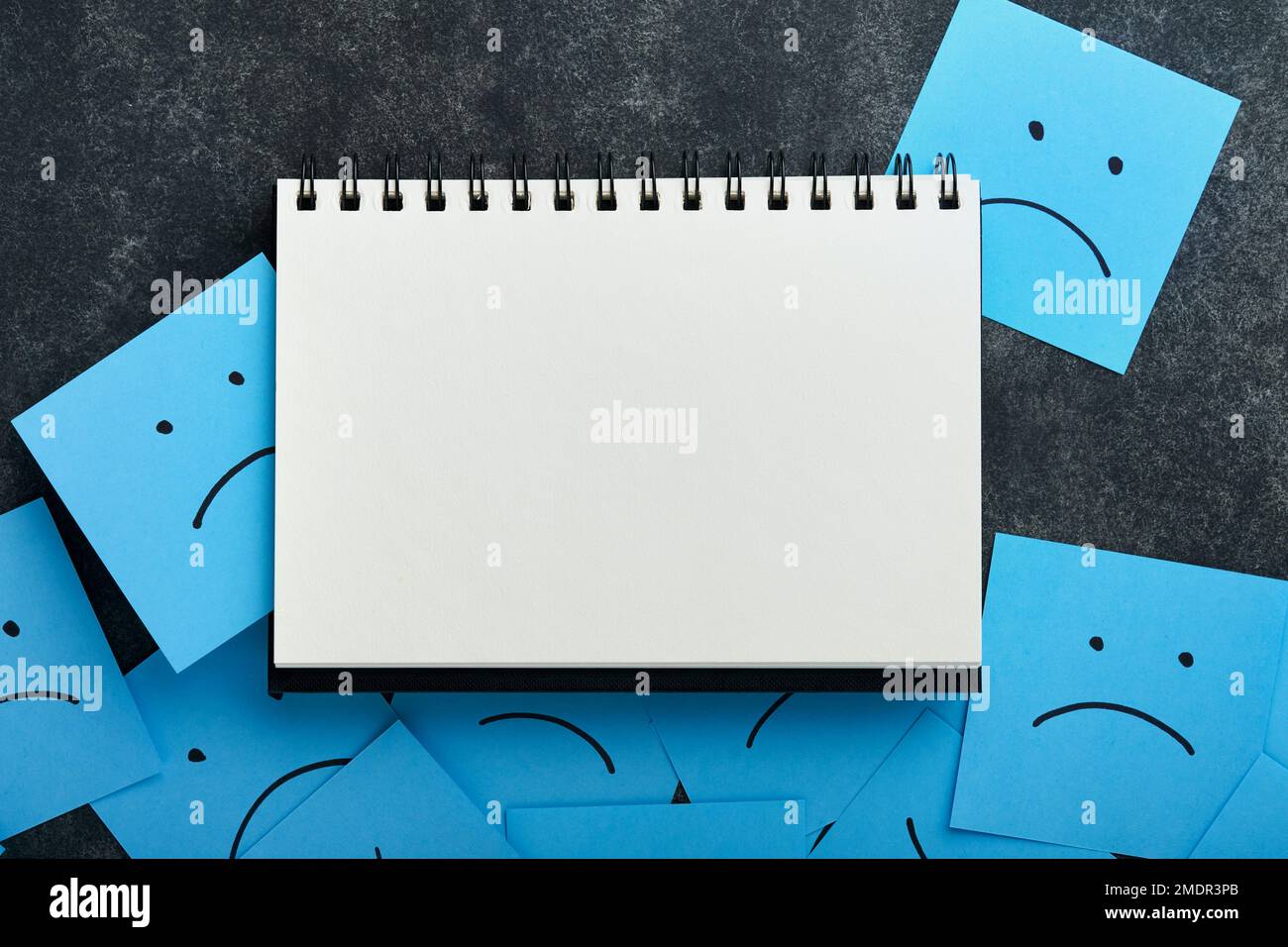 Blue sticky notes blank with drawing sad face on black background with ...