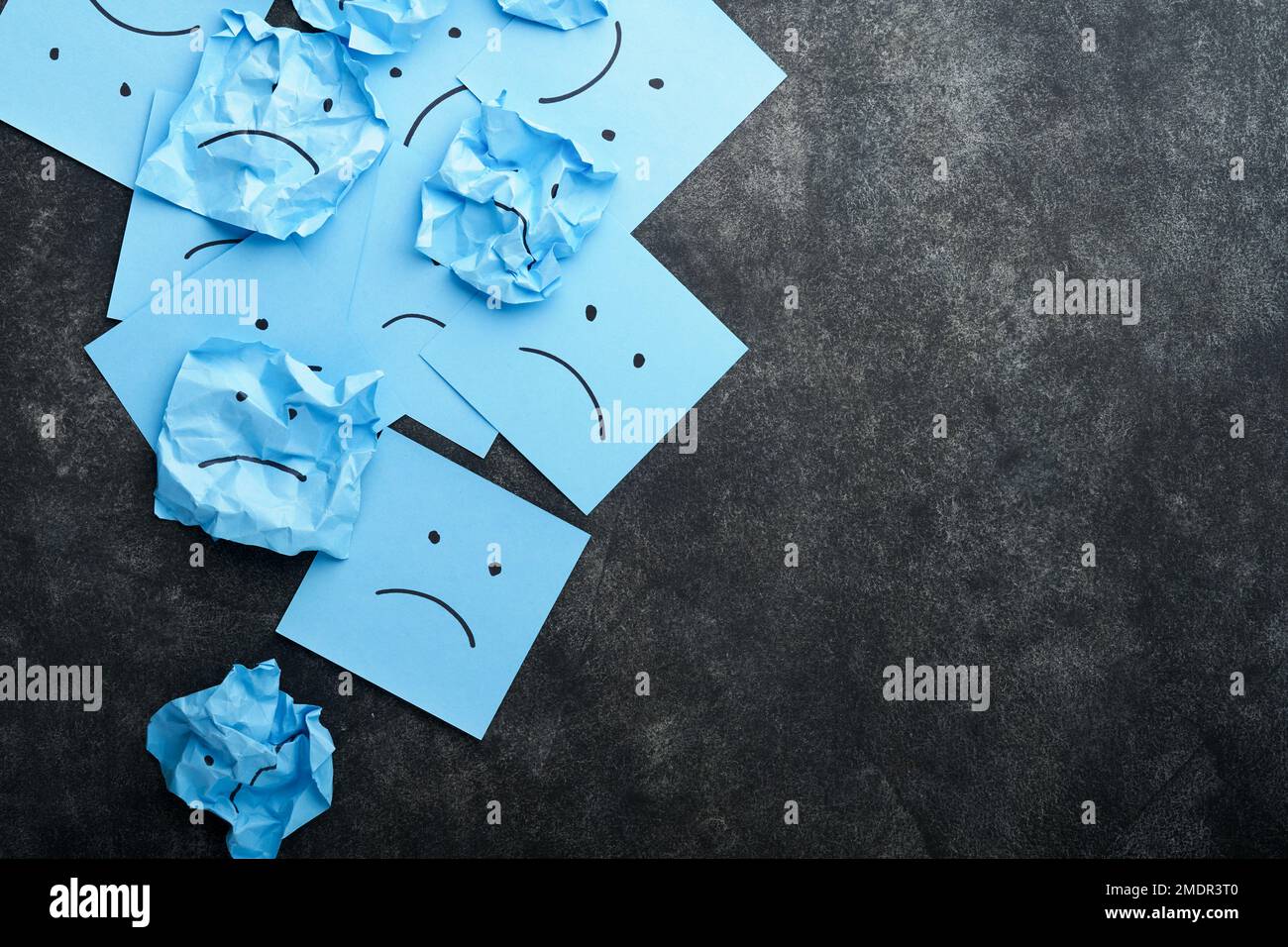 Blue crumpled sticky notes blank with drawing sad face on black ...