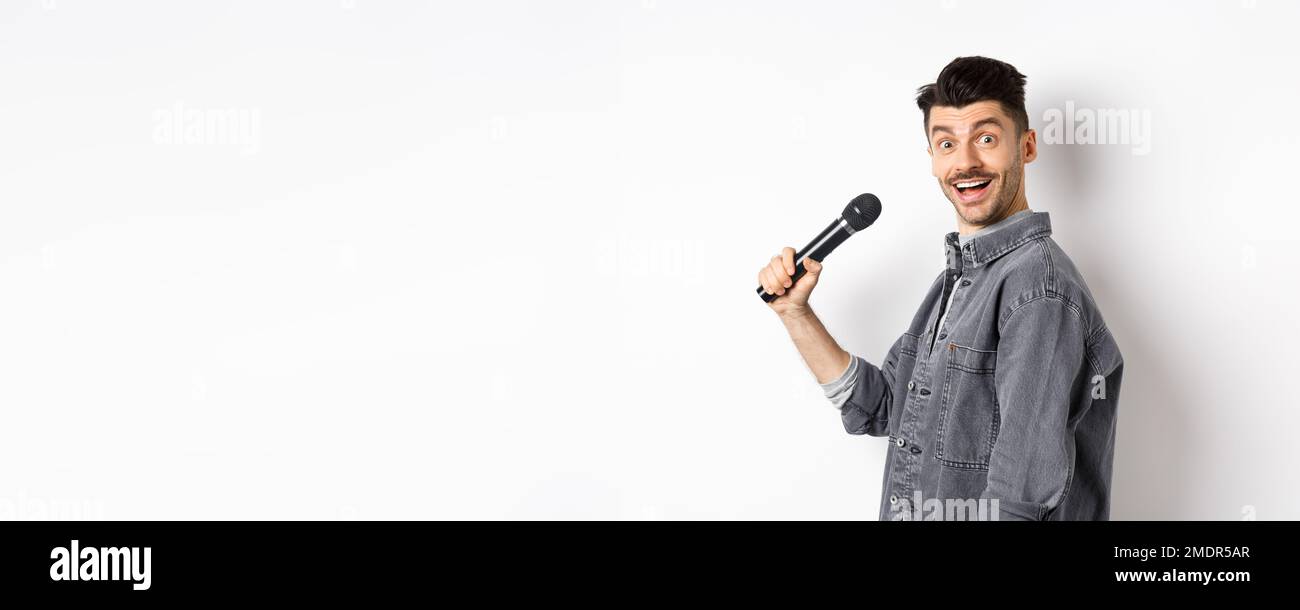Profile of handsome smiling man holding mic, turn head at camera with ...