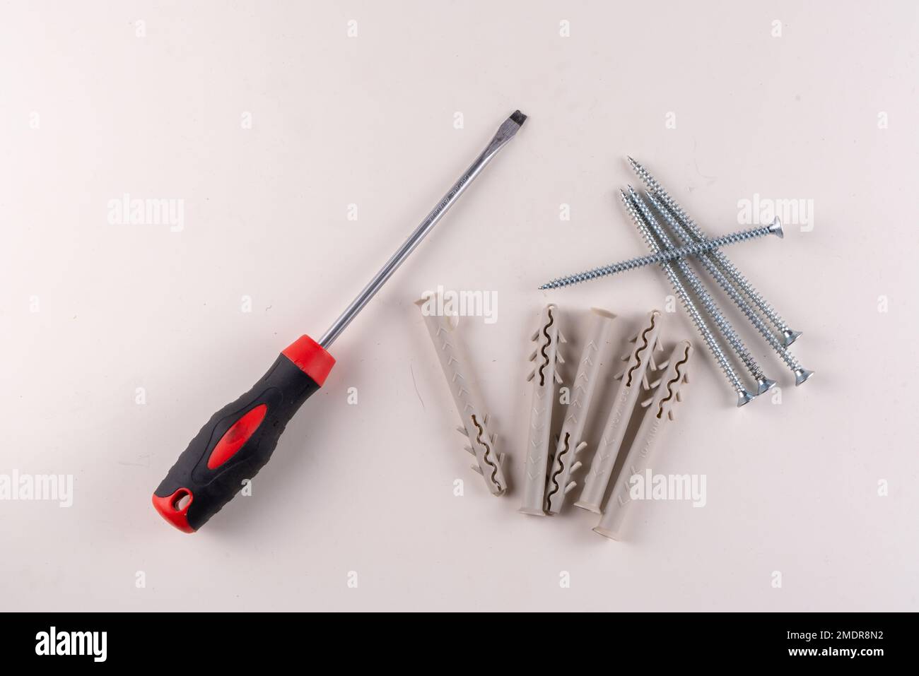 Set of flat head screwdriver, screws and plastic screw anchor plugs ...