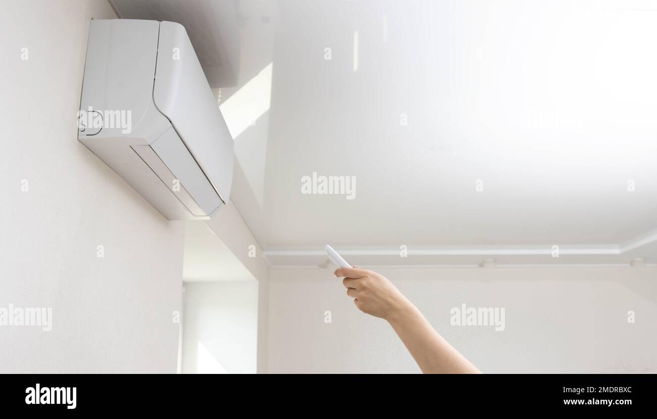 A person controls the air conditioner at home with a remote control ...