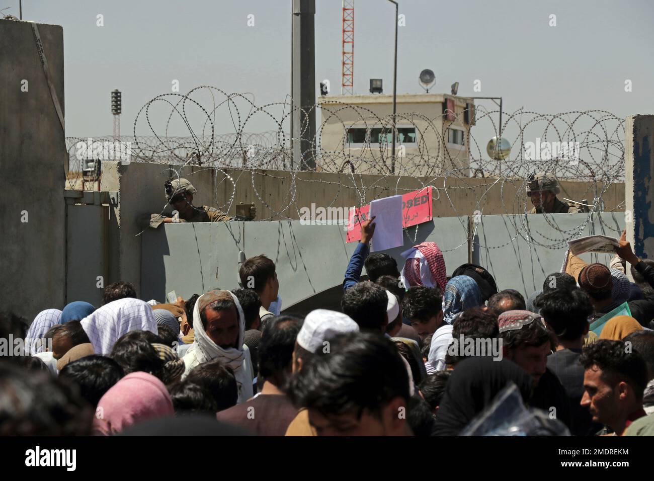 U.S. soldiers stand inside the airport as hundreds of people gather ...